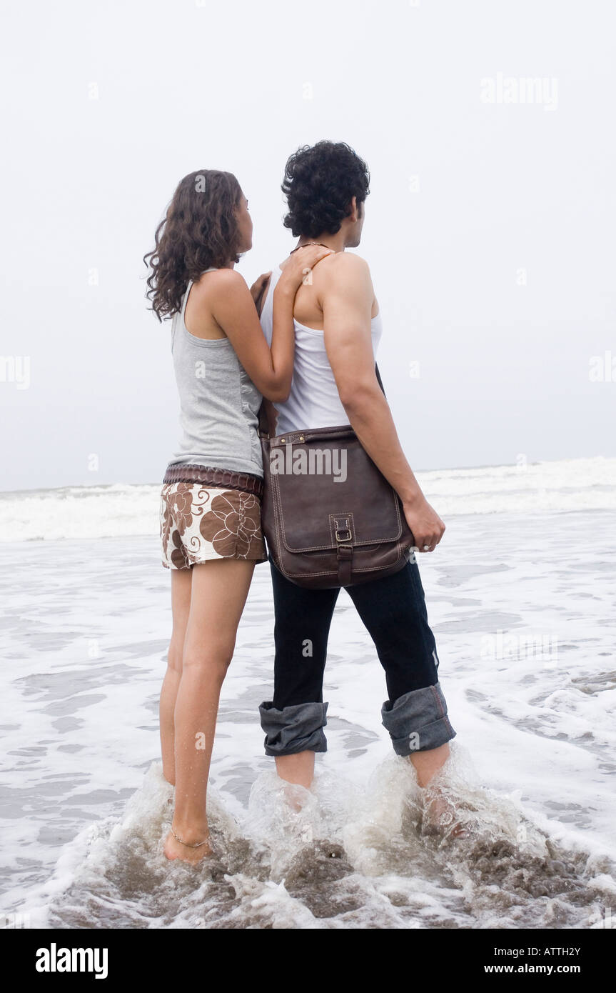 Side profile of a young couple standing on the beach Stock Photo - Alamy