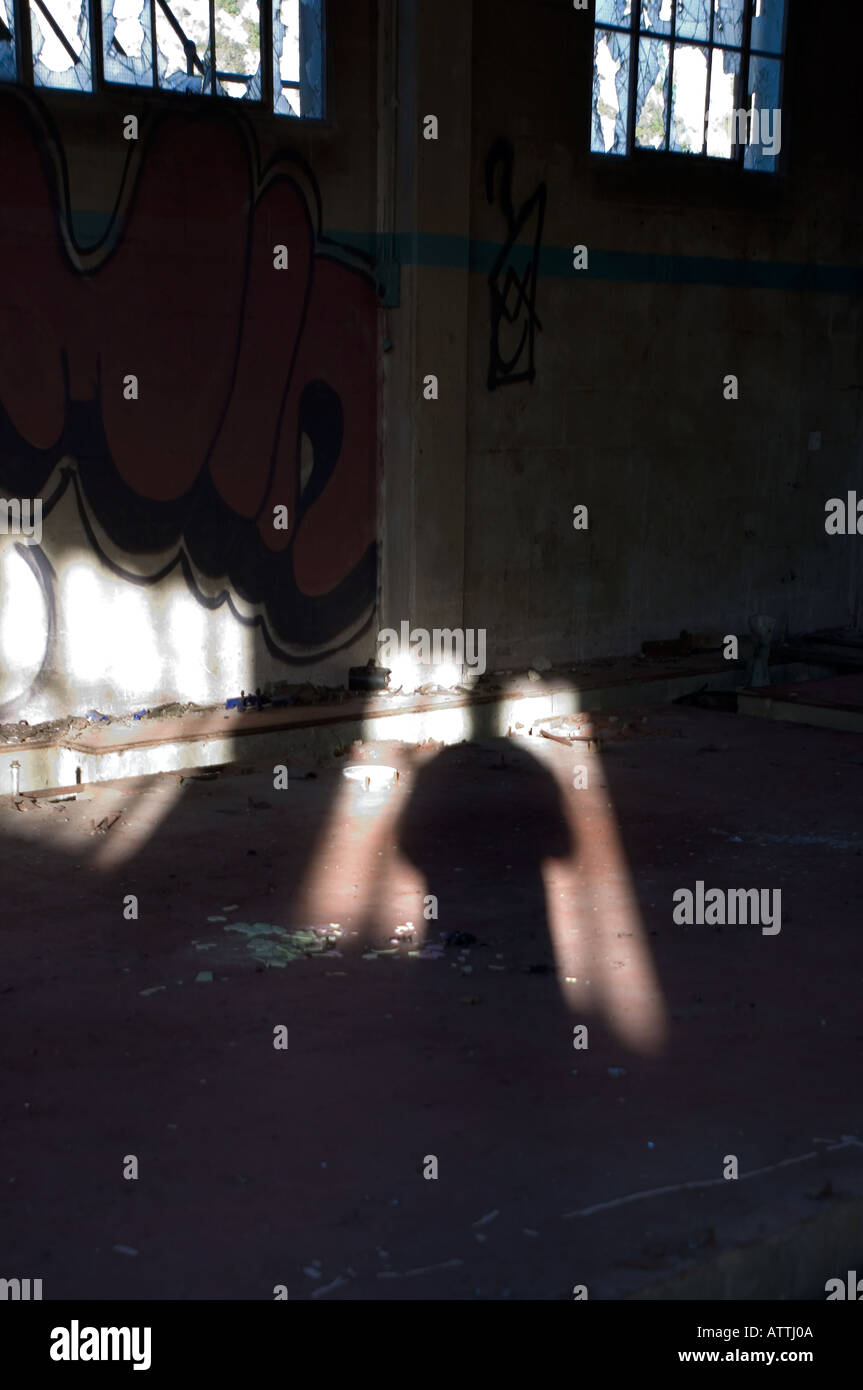 Broken window panes backlit by late evening sun in and the eerie shadow ...