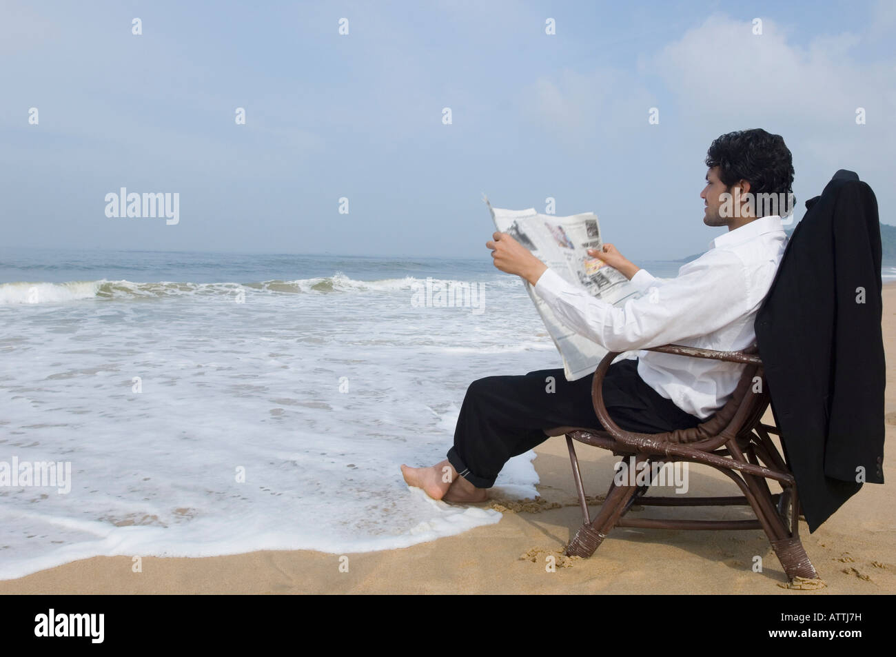 Young man reading a newspaper on the beach Stock Photo - Alamy