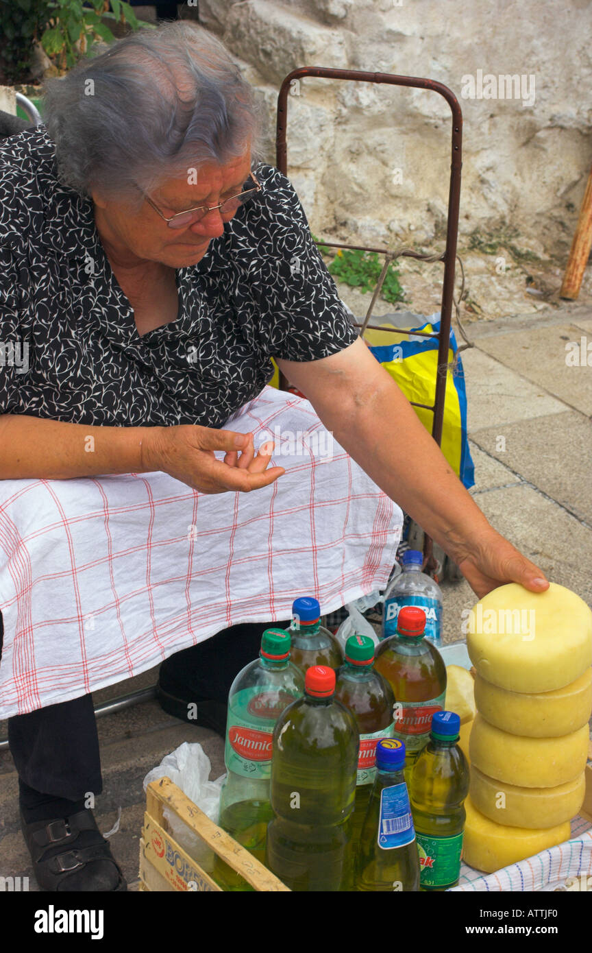 Woman selling cheese and olive oil at market in old town section of ...