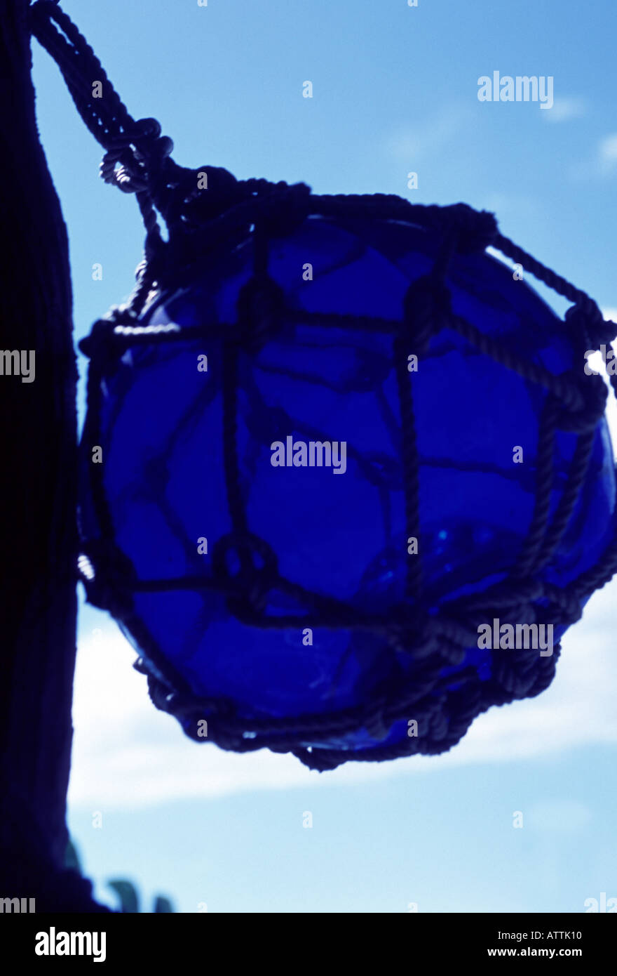 Transparent blue glass fishing float with light through it and sky in ...