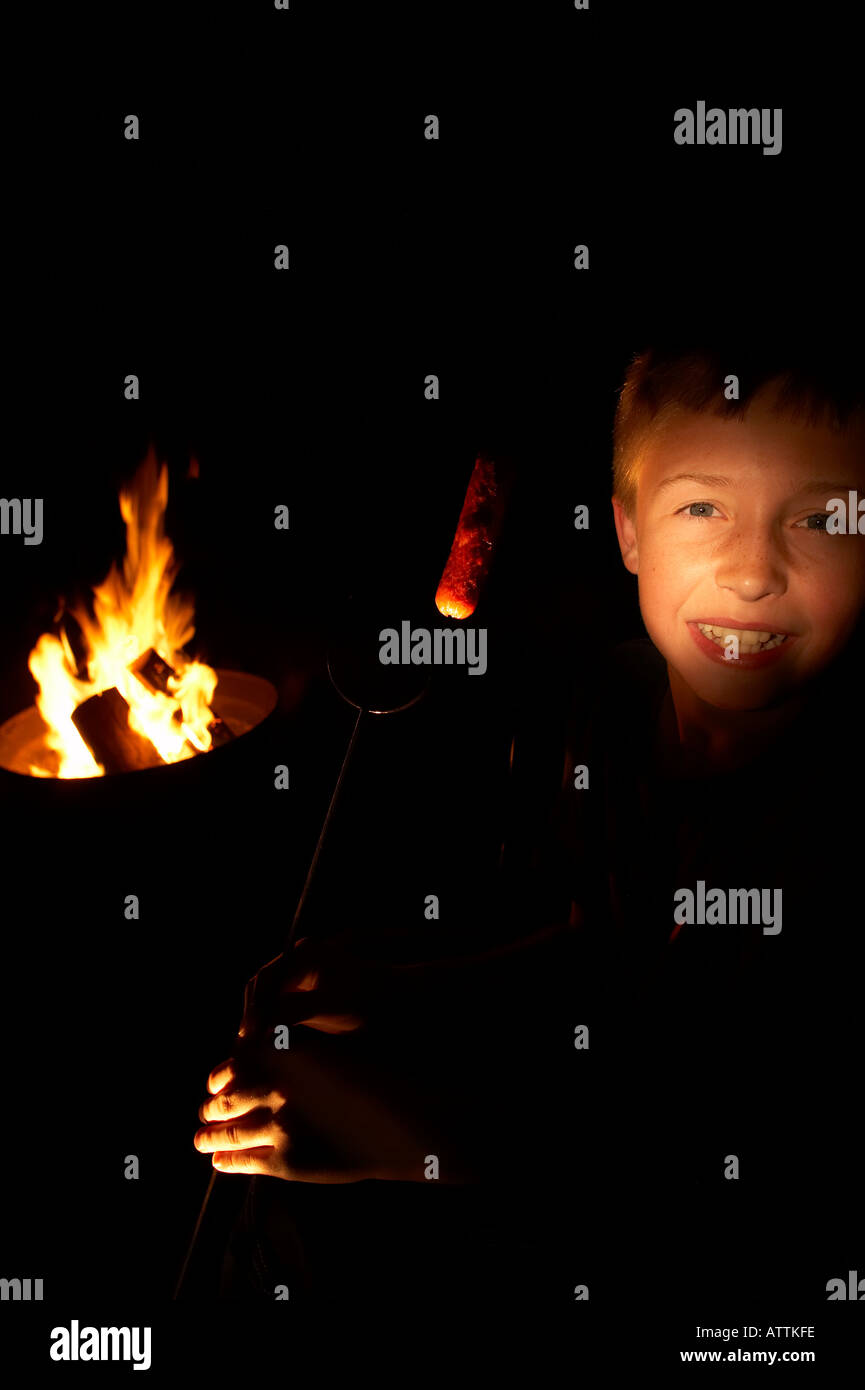 Boy roasting wiener (hot dog) on stick over open fire Stock Photo - Alamy
