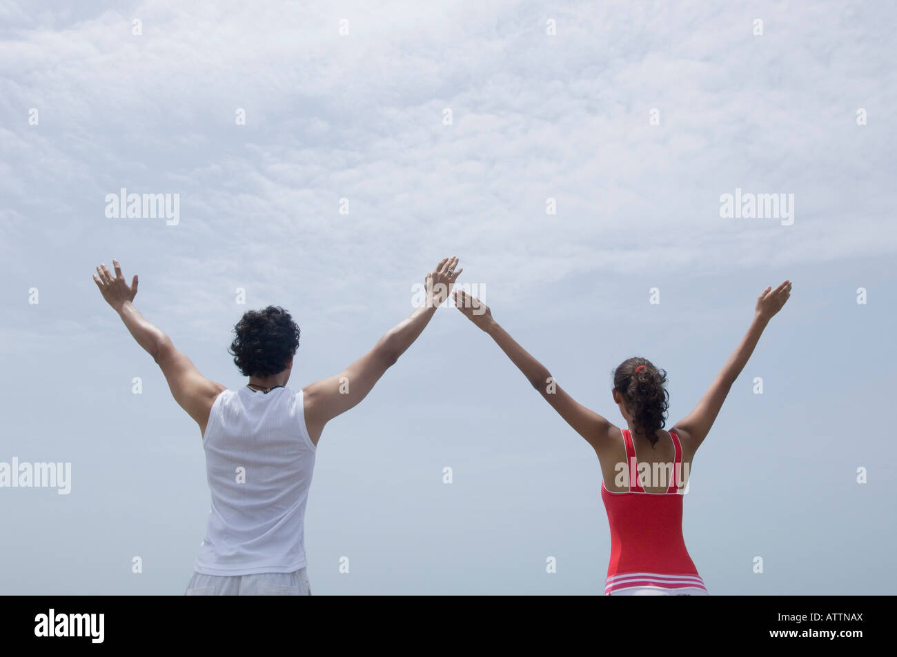 Rear view of a young couple with their arms raised Stock Photo - Alamy