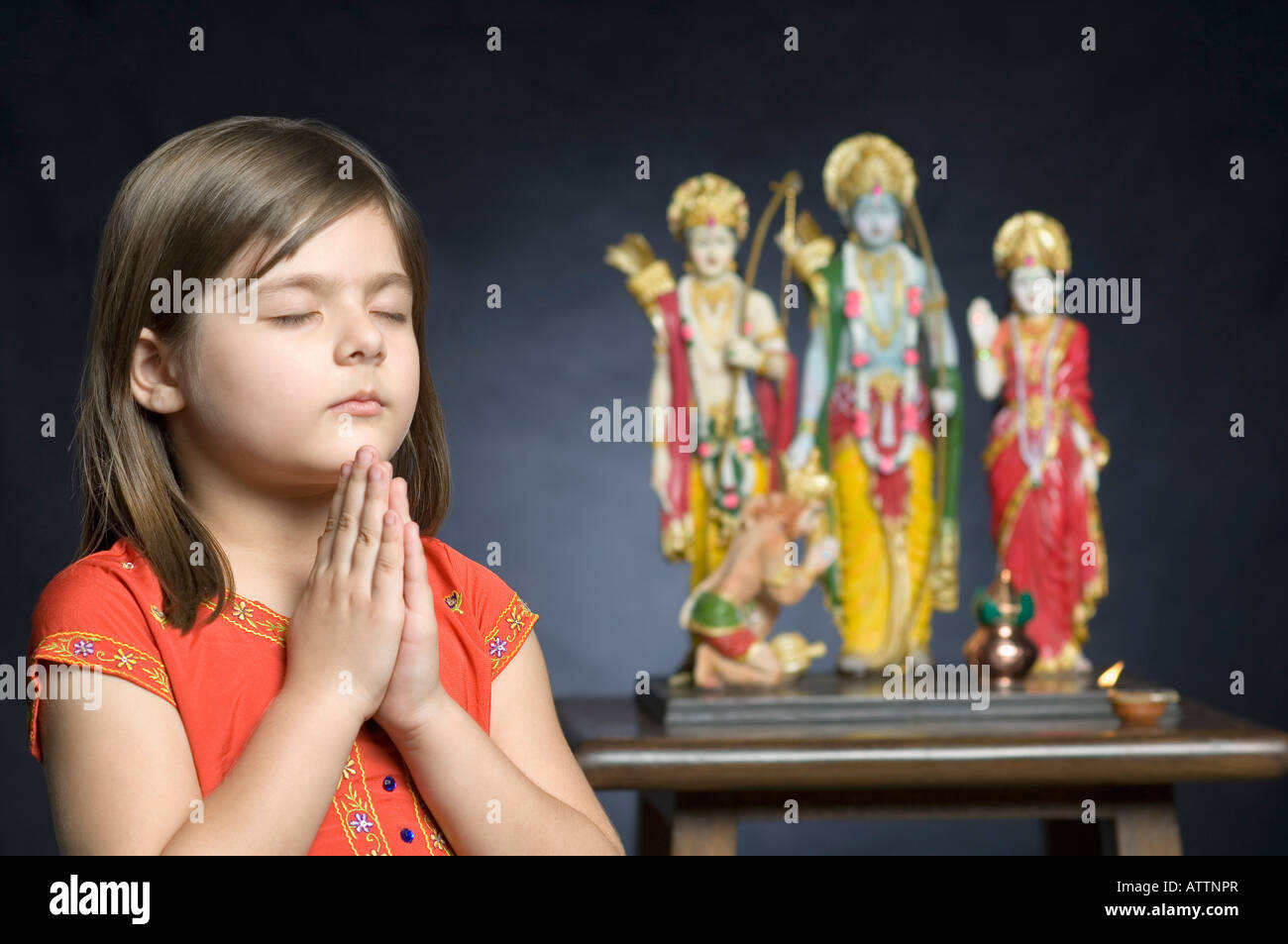 Close-up of a girl praying with statues of God beside her Stock Photo ...