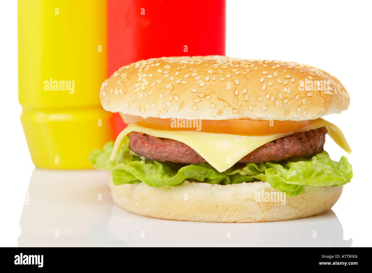 Cheeseburger with mustard and ketchup bottles reflected on white ...