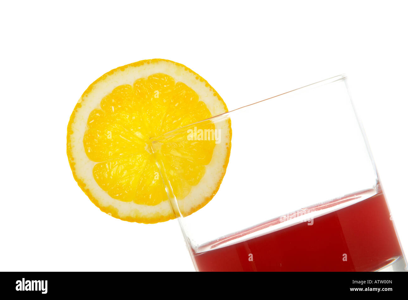A glass of red juice with a lemon slice reflected on white background ...