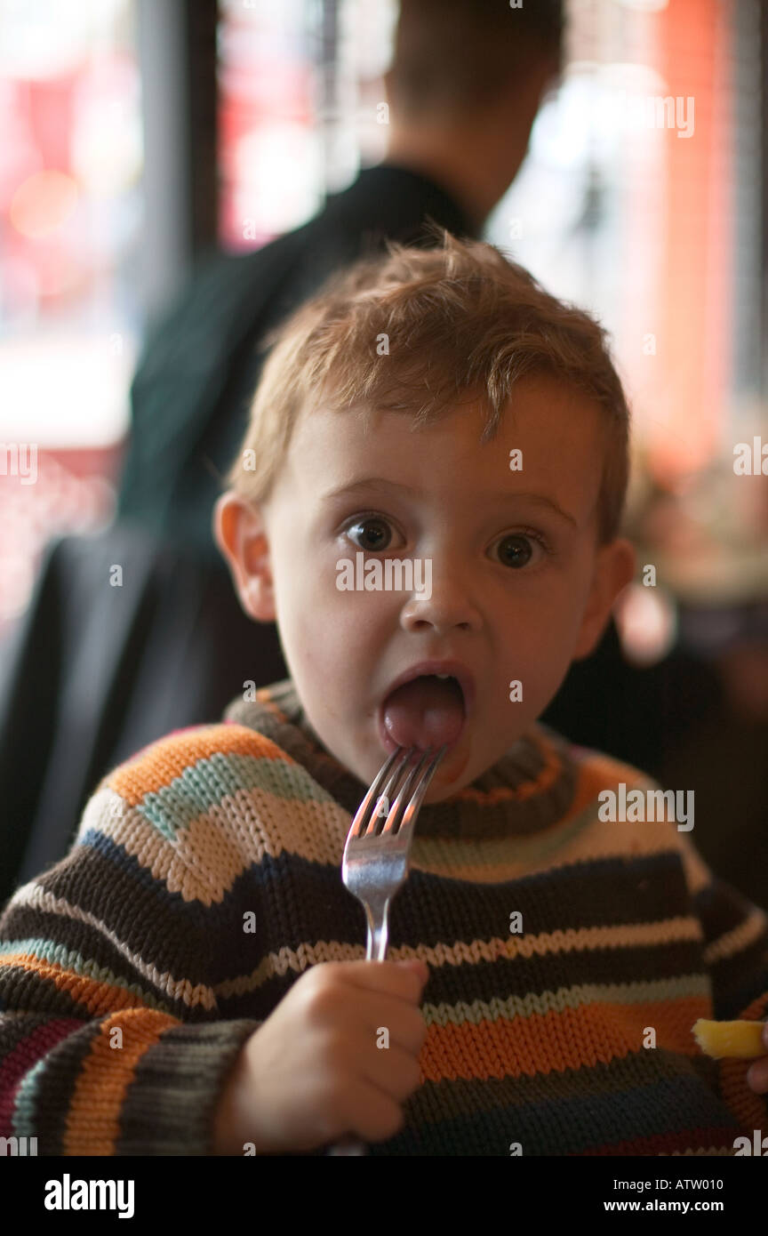 little boy toddler eating in a restaurant wearing a striped sweater ...