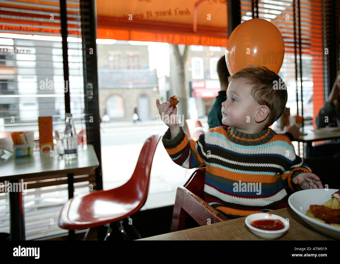 little boy toddler eating in a restaurant wearing a striped sweater ...