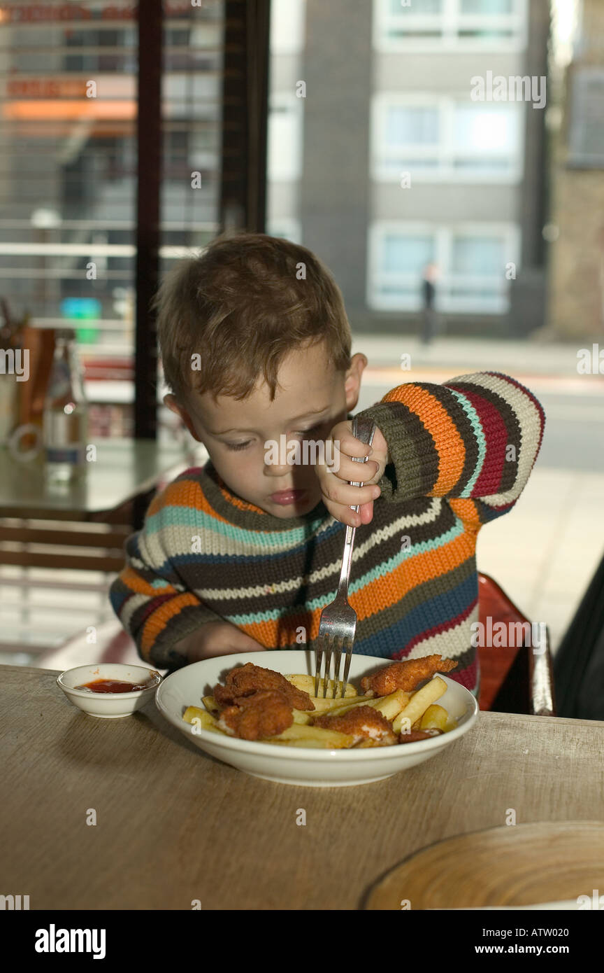 little boy toddler eating in a restaurant wearing a striped sweater ...