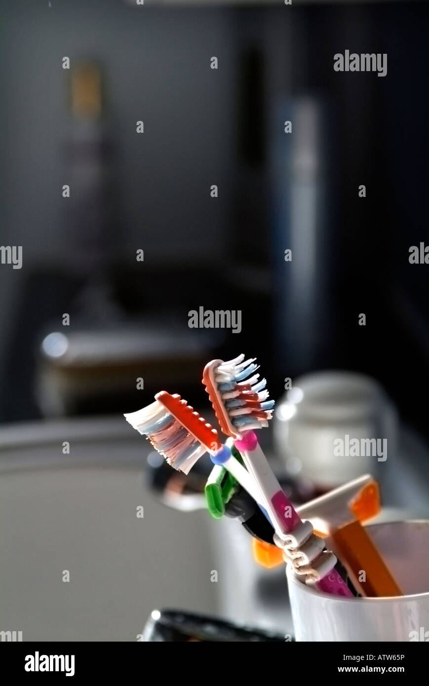 toothbrushes and disposable razor in mug in bathroom Stock Photo - Alamy