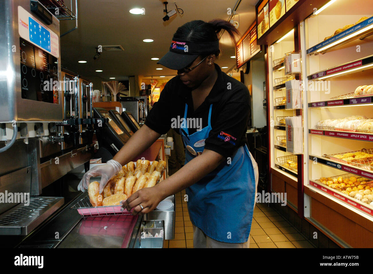A worker arranges a display of donuts in a New York City Dunkin Donuts ...
