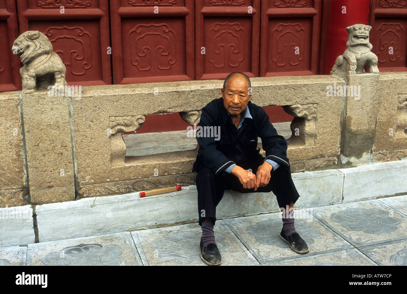 An old man takes a rest in a beautiful Chinese buddhist temple compound ...
