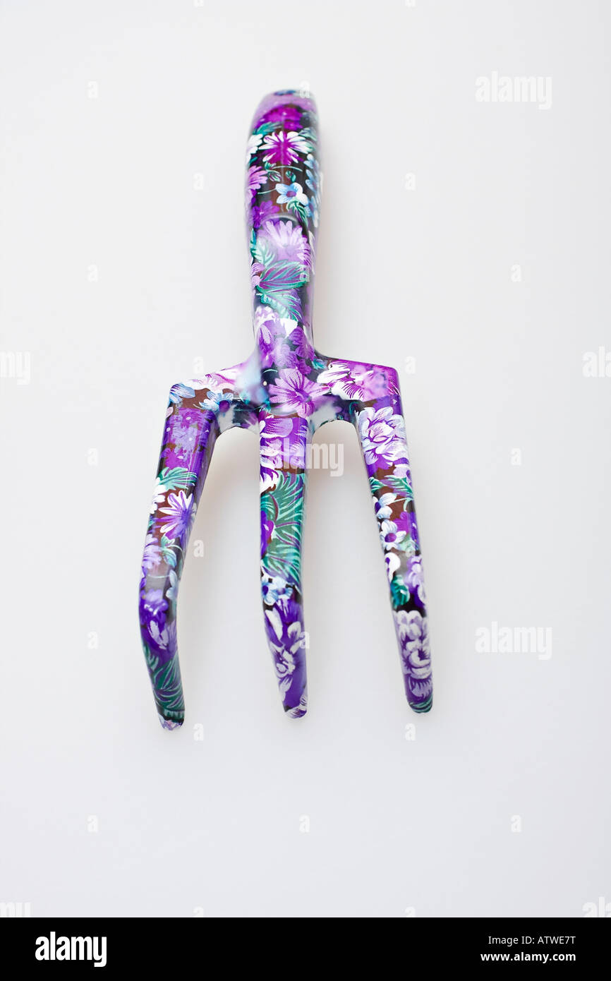 A single flowery purple girly gardening fork against a plain white ...