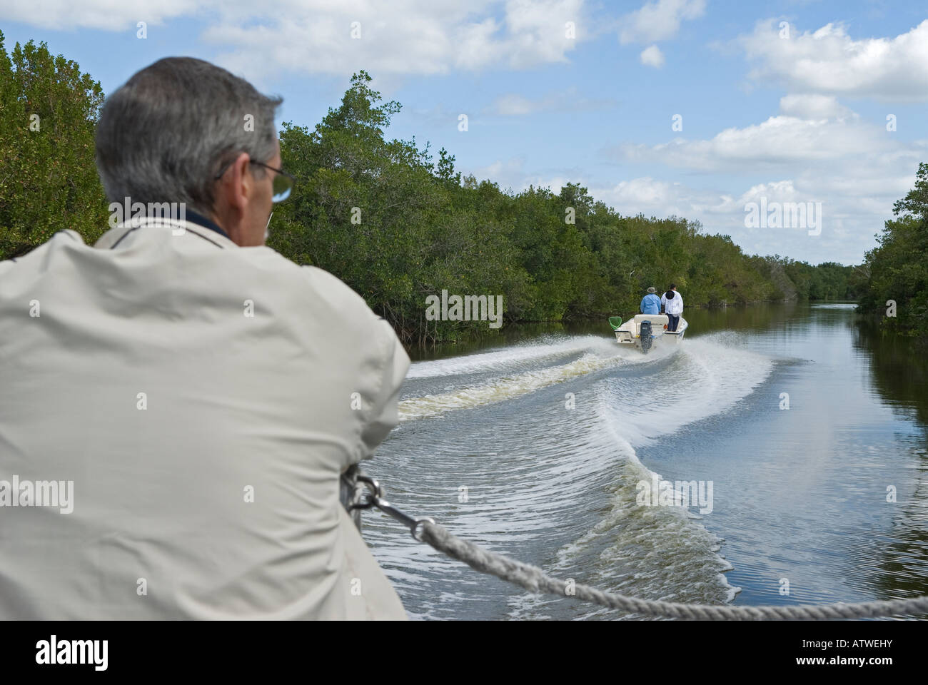 A speedboat driven by 2 people speeds by a touring boat in the Florida ...