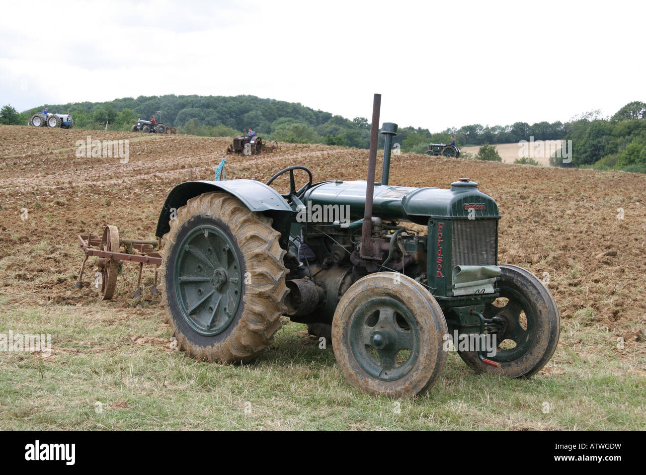Vintage tractor on ploughed field with others at work Stock Photo - Alamy