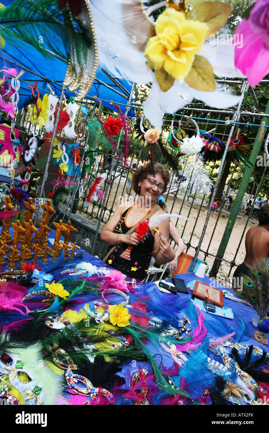 Stall lady shows off bright colour costume jewellery, masks, in street ...