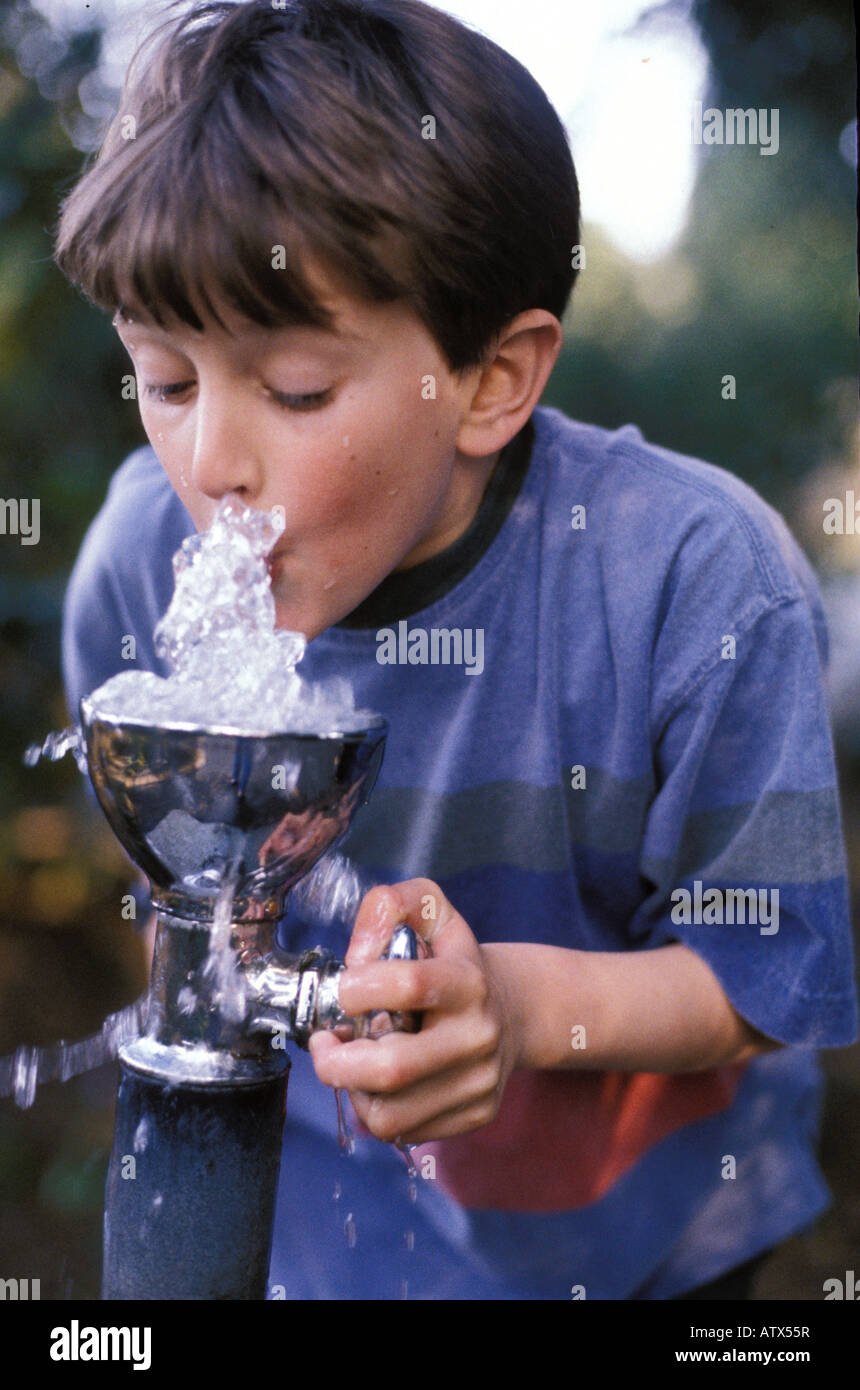 Boy drinking water from fountain in park Stock Photo - Alamy
