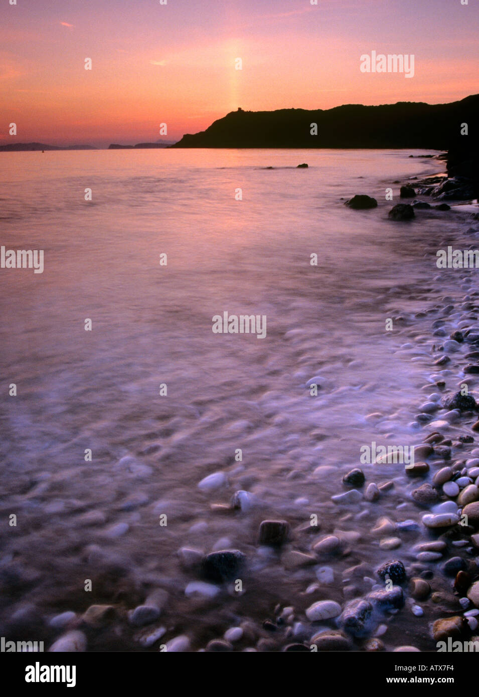 Sunset over Arillas Bay Corfu with orange sky and rocks on beach with ...