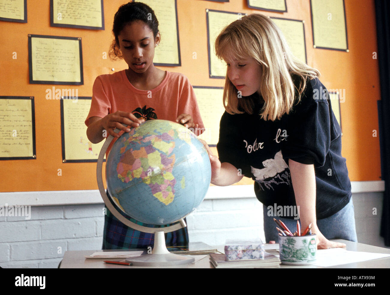 Secondary school children learning geography by studying a world globe ...