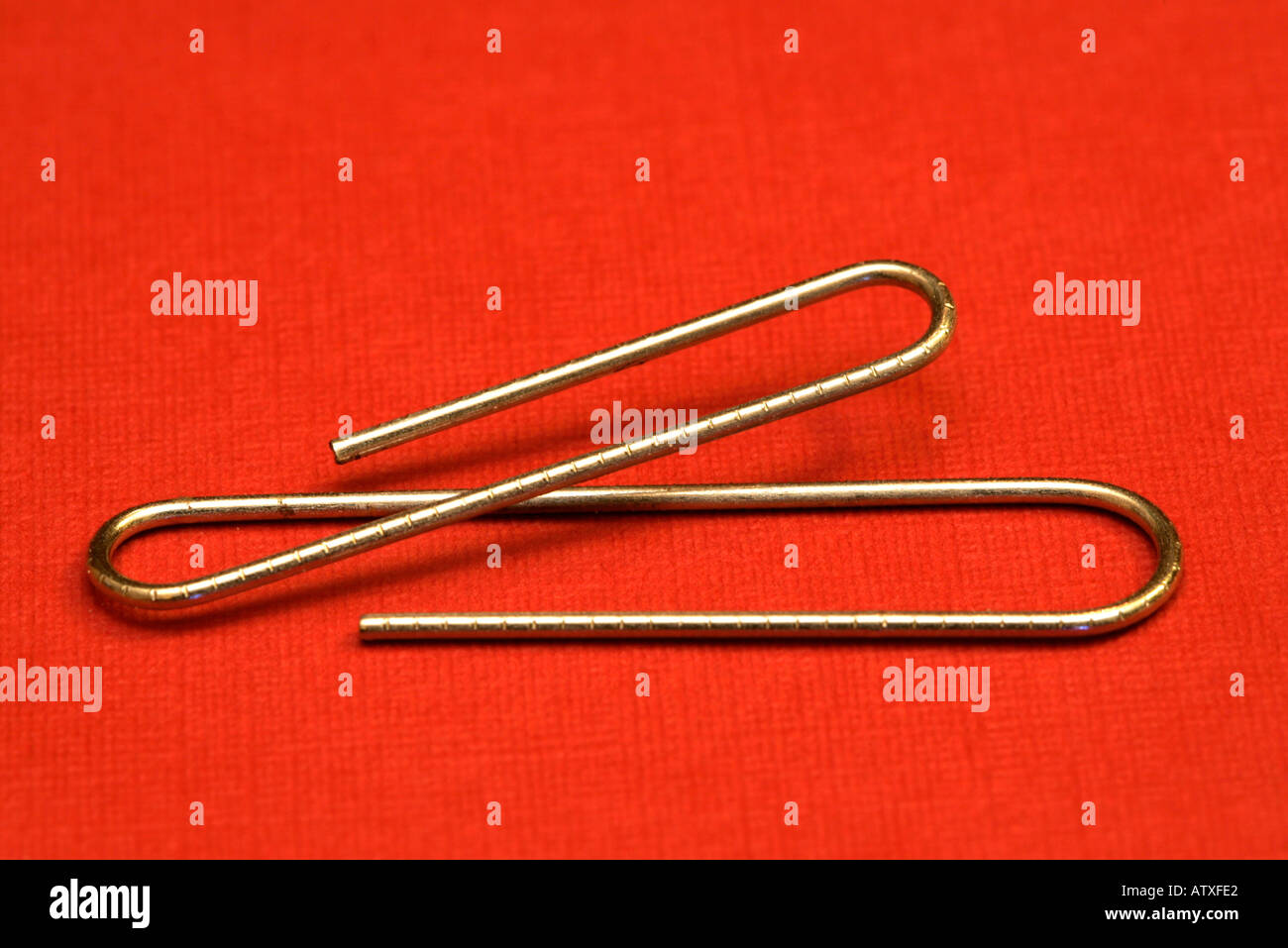 Bent paper clip on red background Stock Photo - Alamy