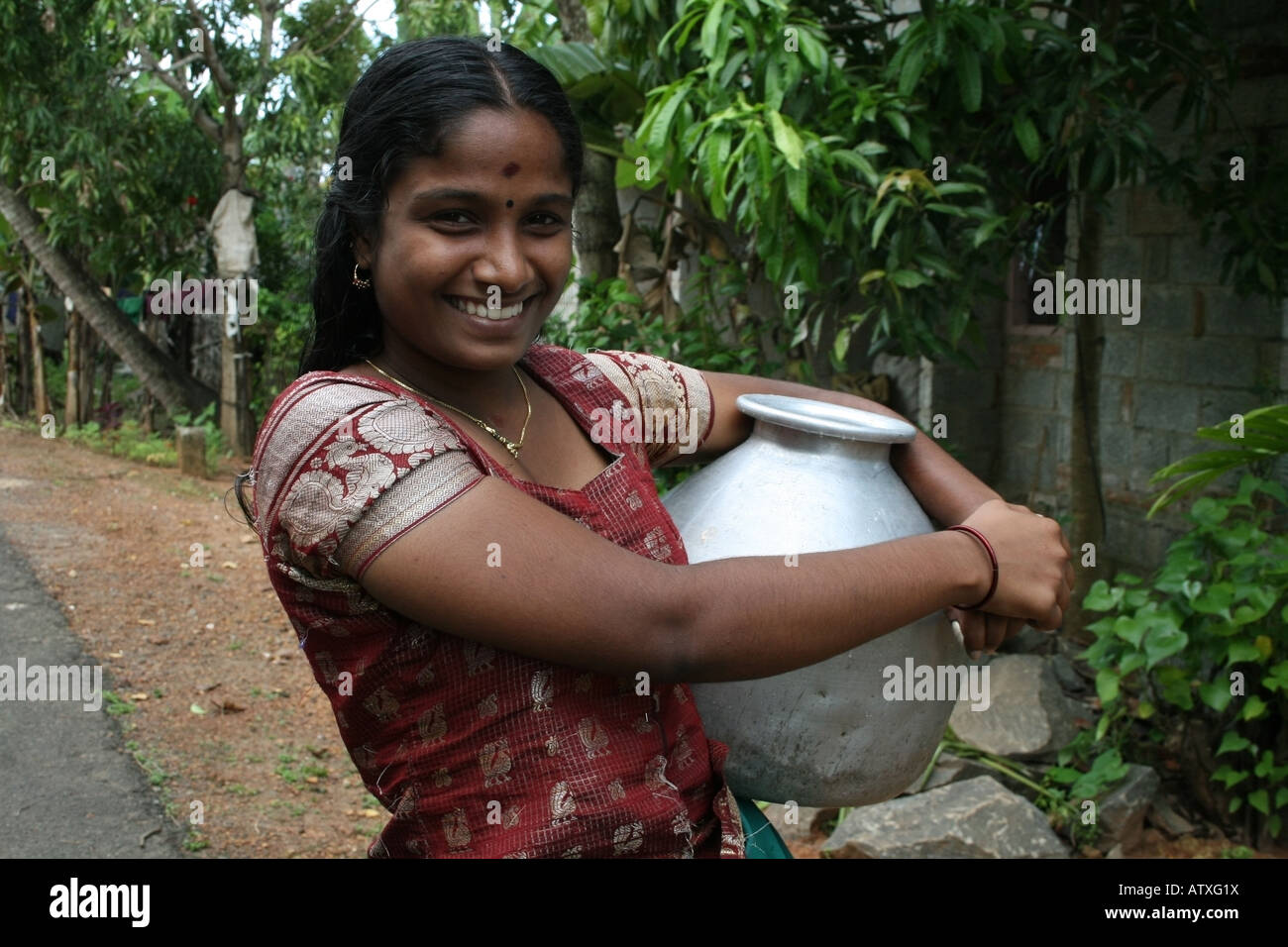 Young Indian lady carrying a metal pitcher of water, Kerela, India ...