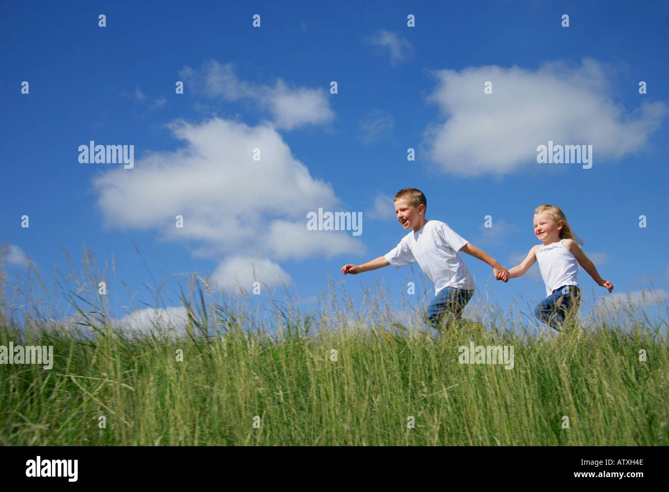 Boy & girl running in tall grass Stock Photo - Alamy