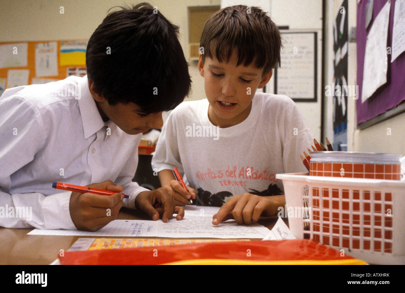 Two pupils at a primary school comparing notes on a school project ...