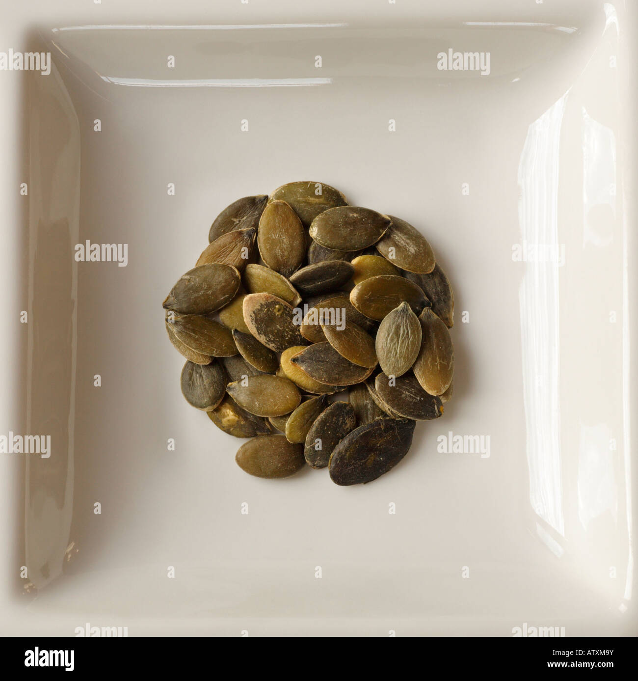 Pumpkin seeds arranged in a circle on a white ceramic dish Stock Photo ...