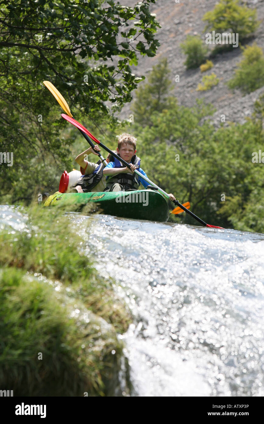 Boy tourist paddling in river kayak over rapids and waterfalls on ...