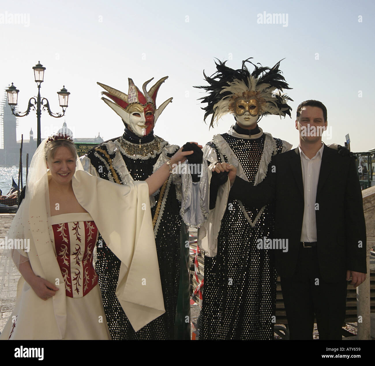 Bride and Groom during with masked participants of the Carnevale Venice ...