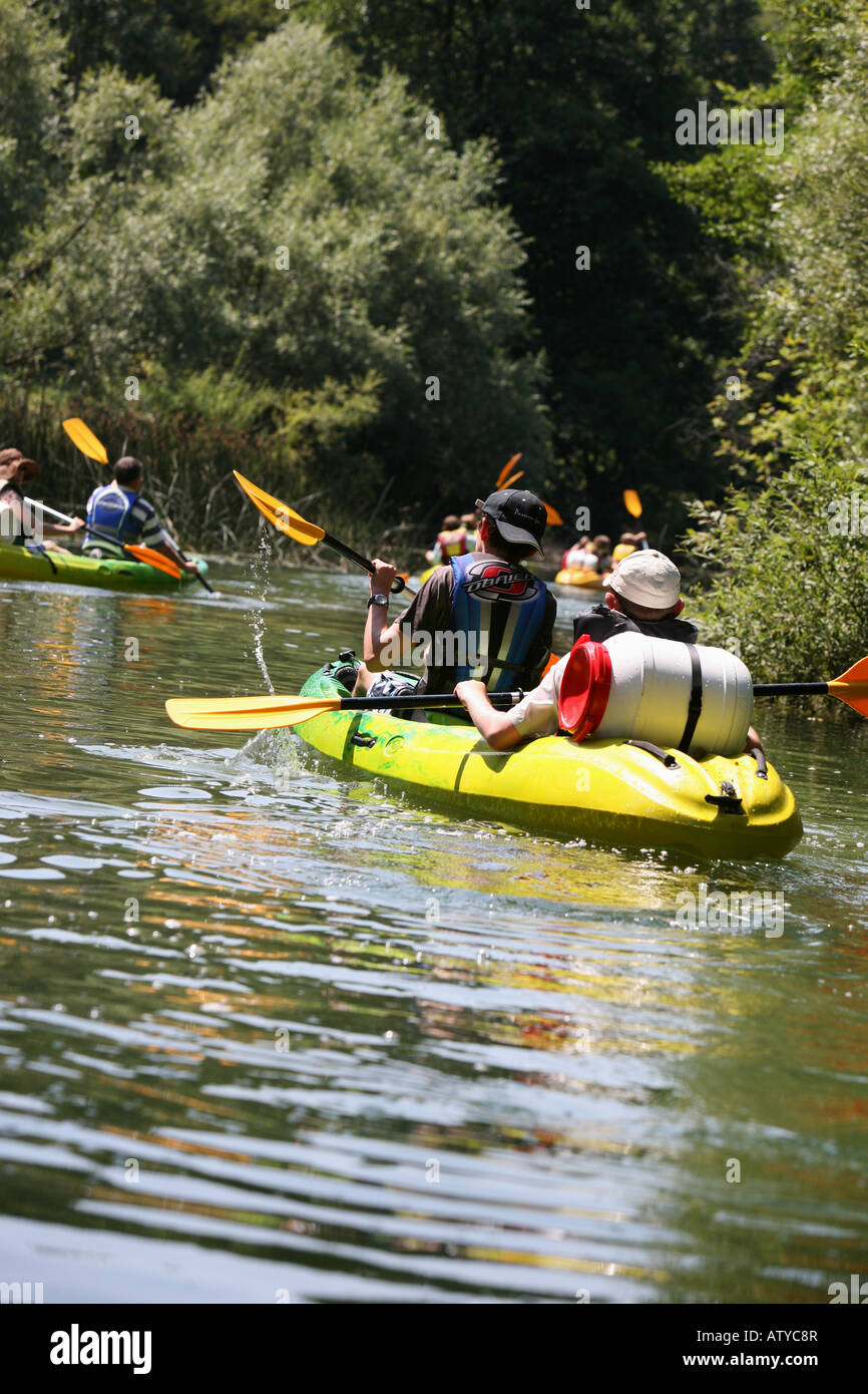 Boy tourists and families paddling in river kayaks over rapids and ...