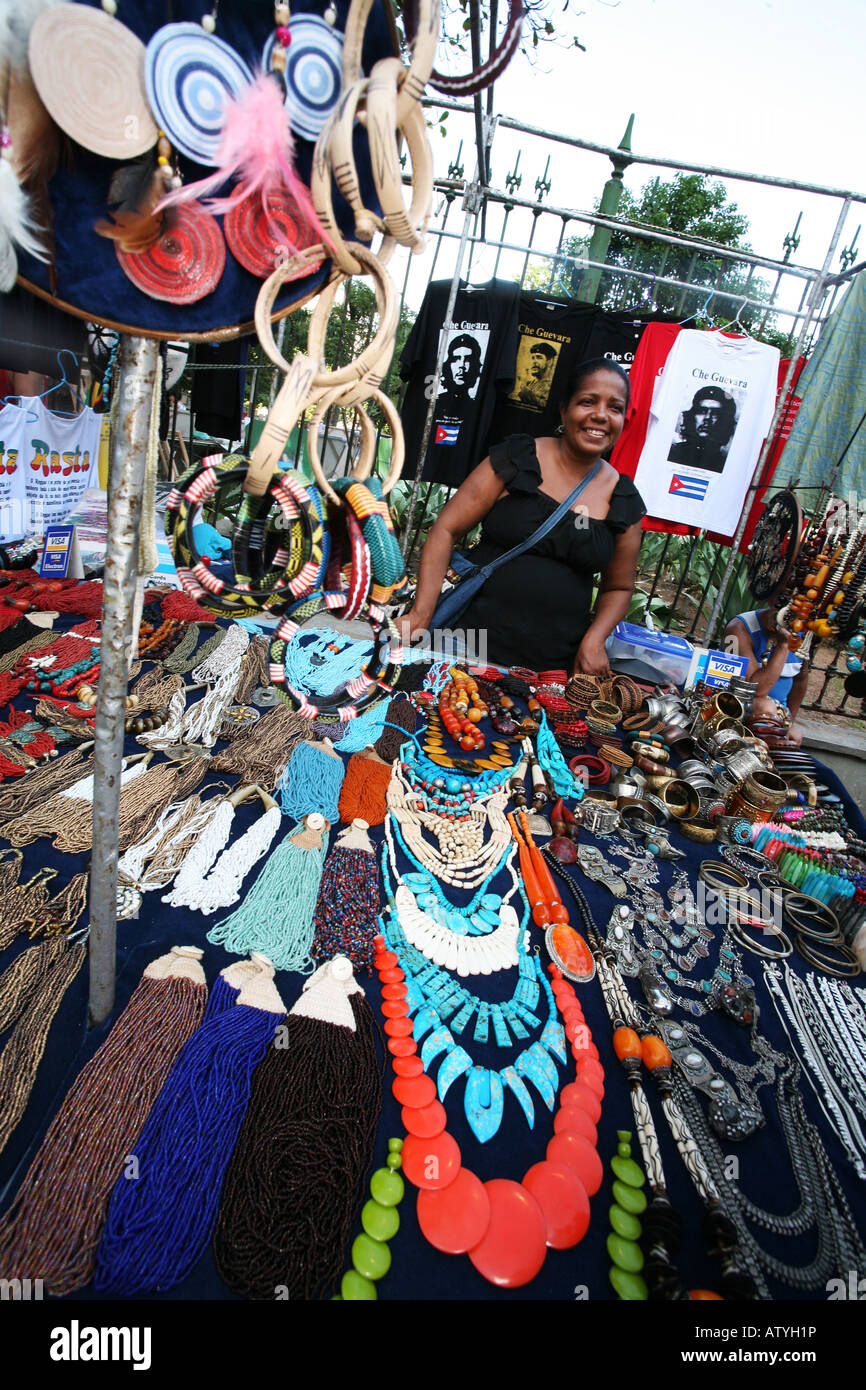 Stall lady shows off bright colour costume jewellery, masks, in street ...