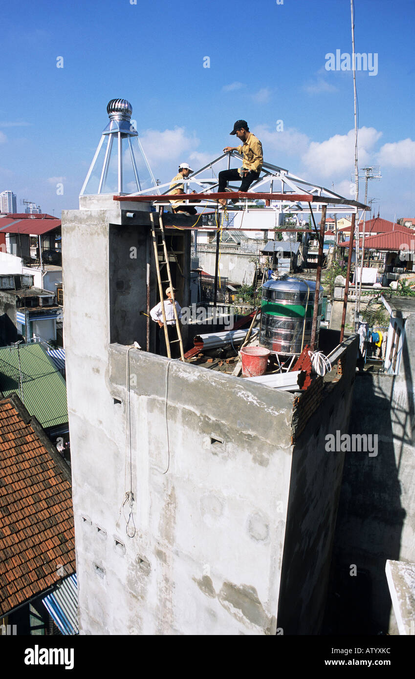 Three men constructing a rocket building on a roof top in Hanoi Stock ...