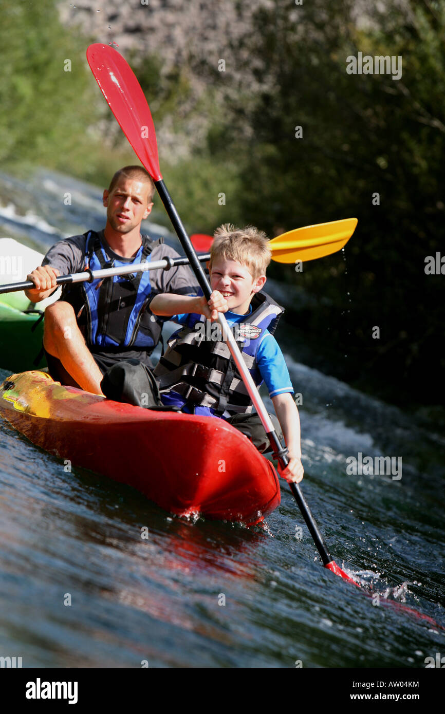 Boy tourist and guide paddling in river kayak over rapids and ...
