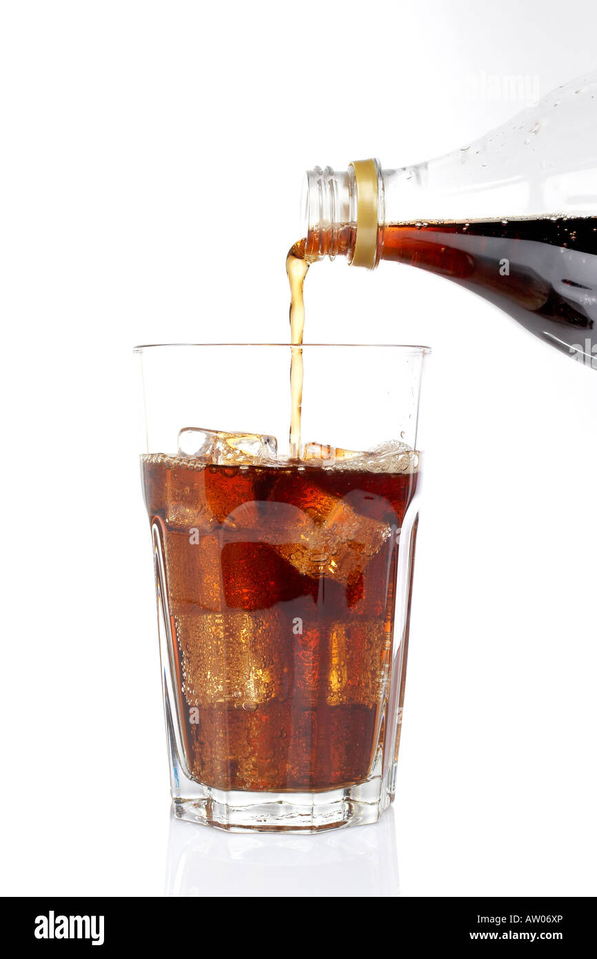 Pouring soda into a glass with ice cubes reflected on white background ...