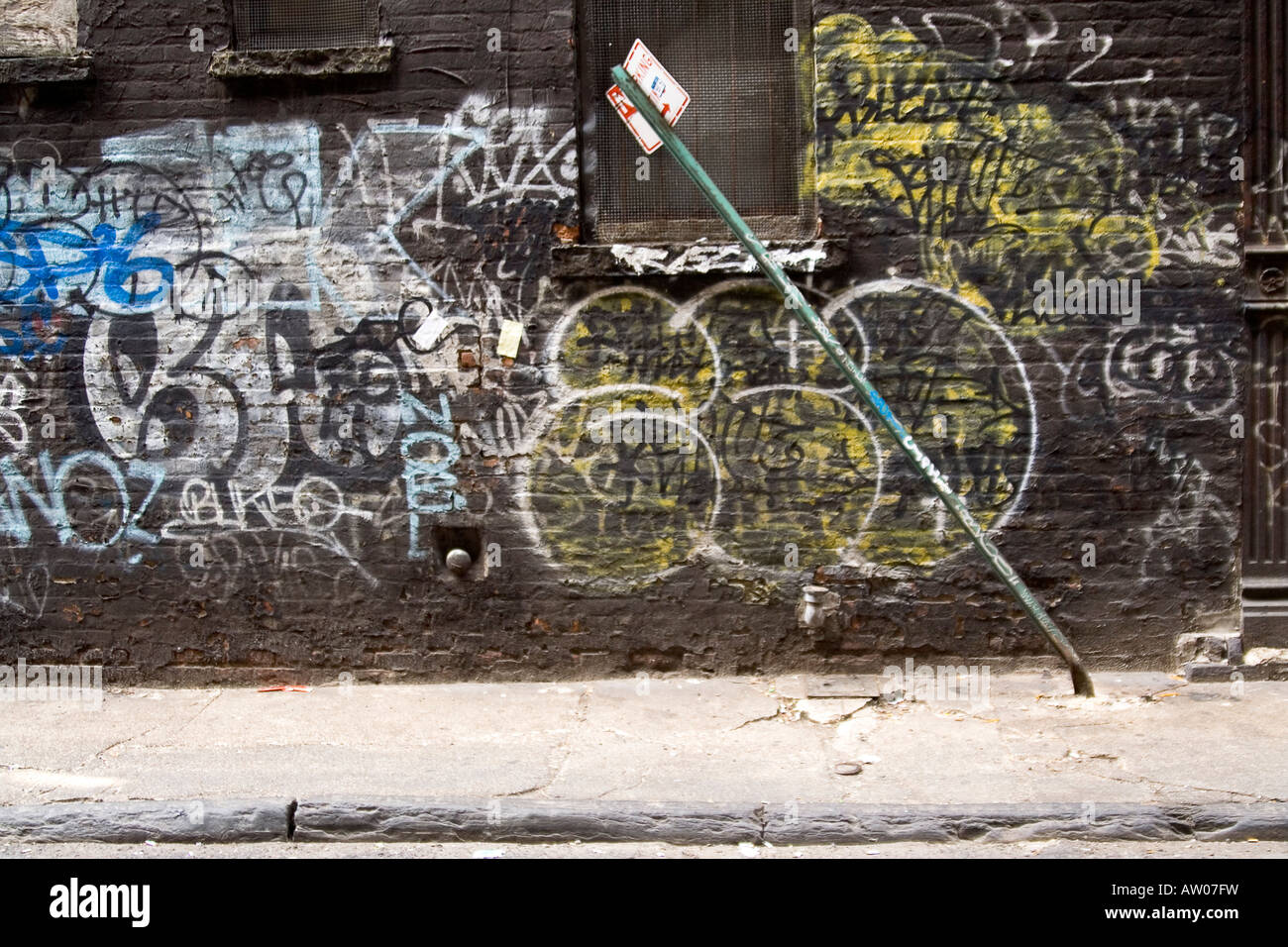 Brick wall painted with graffiti. Shot from back alley under the ...