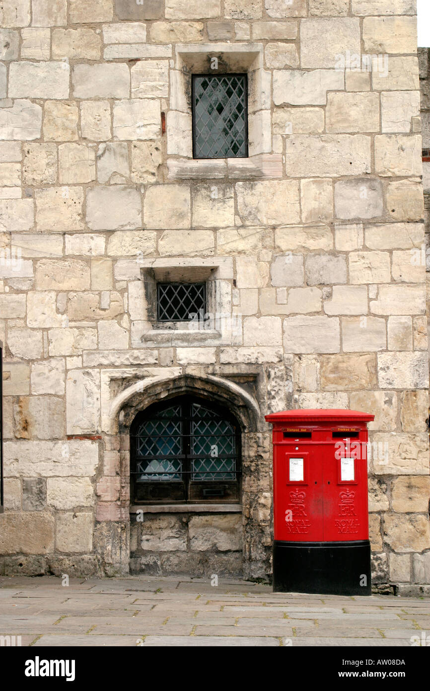 Red post box standing at side of ancient window with diamond leaded ...