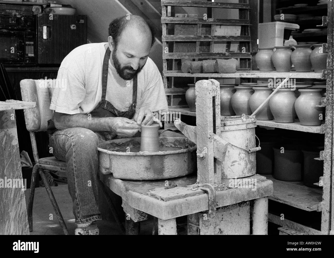 A potter works throwing ceramic pots in his studio producing near ...