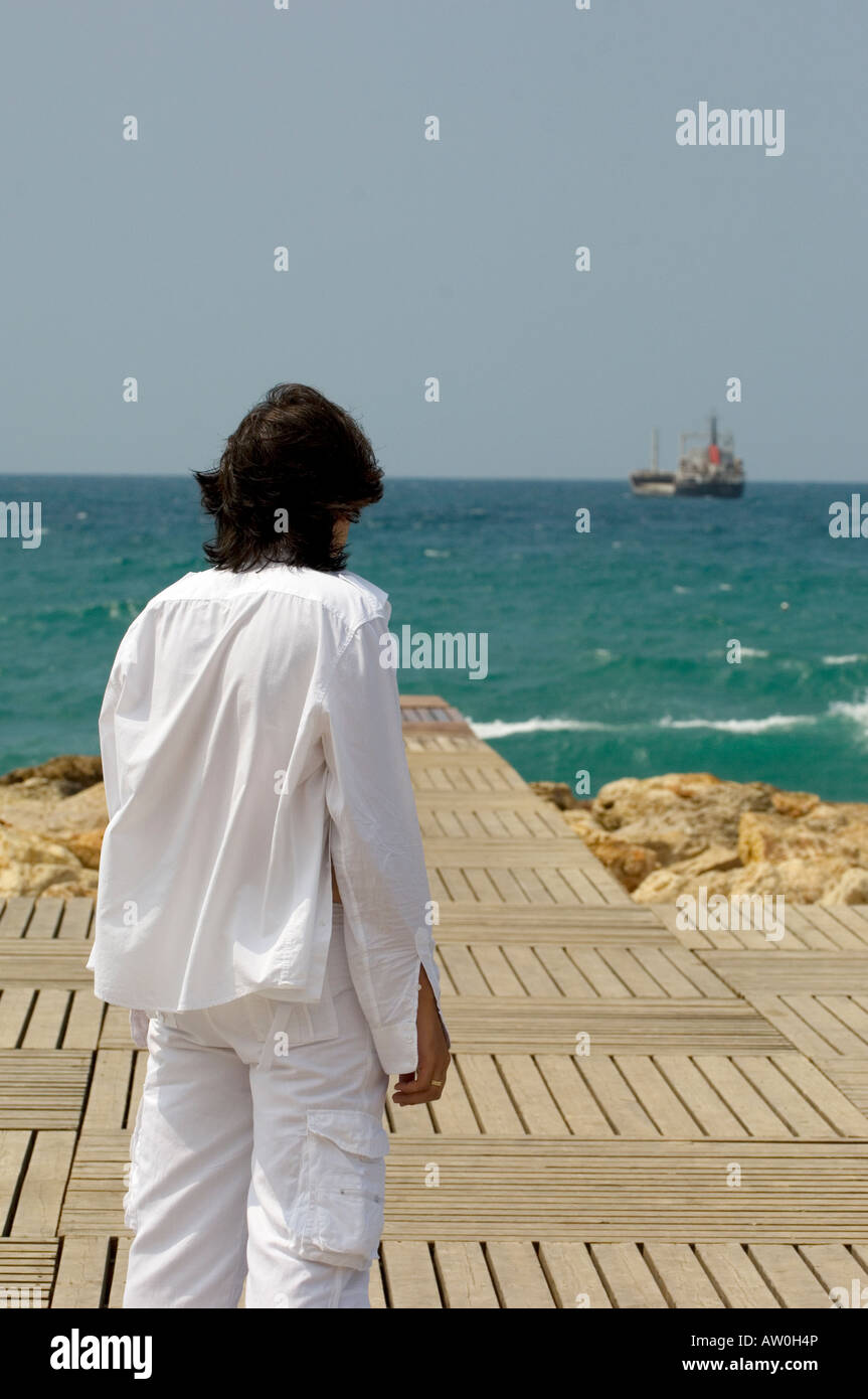 Man standing on wharf watching ship leaving Stock Photo - Alamy