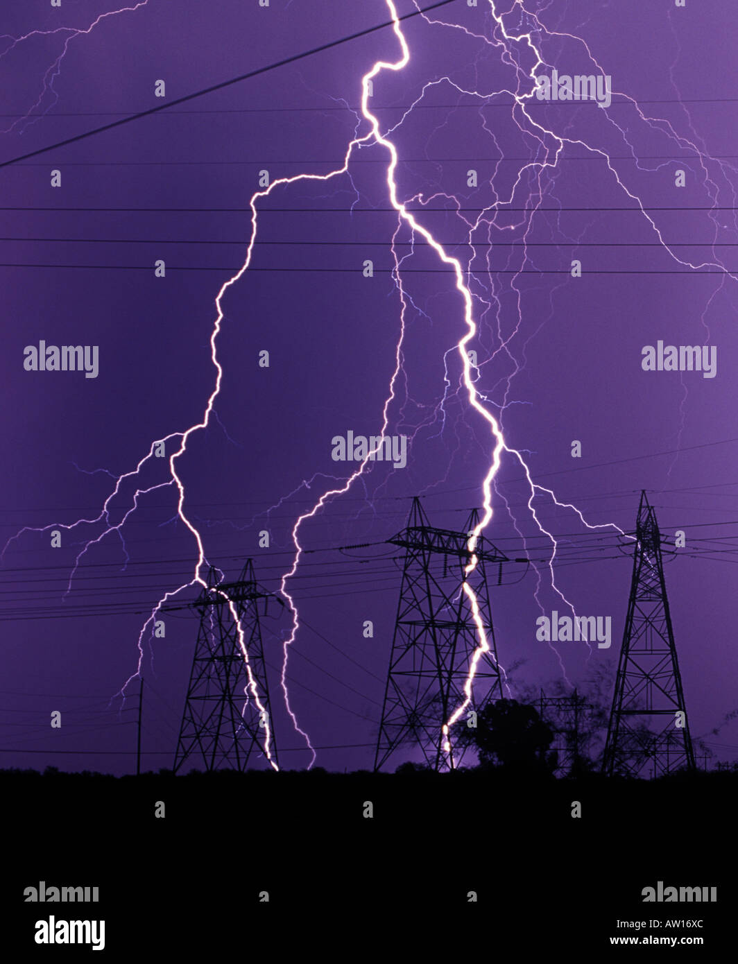 Lightning strikes against a dark purple sky near powerlines and power ...