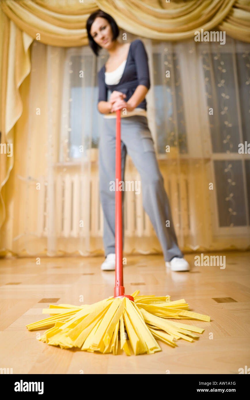 Woman standing in room with mop Focused on mop Looking at camera Whole ...