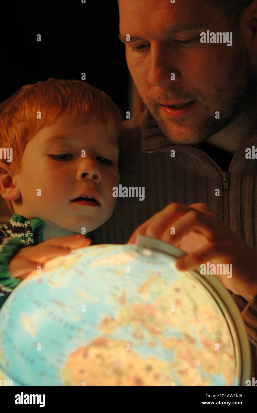 Father studies a globe with his child Stock Photo - Alamy
