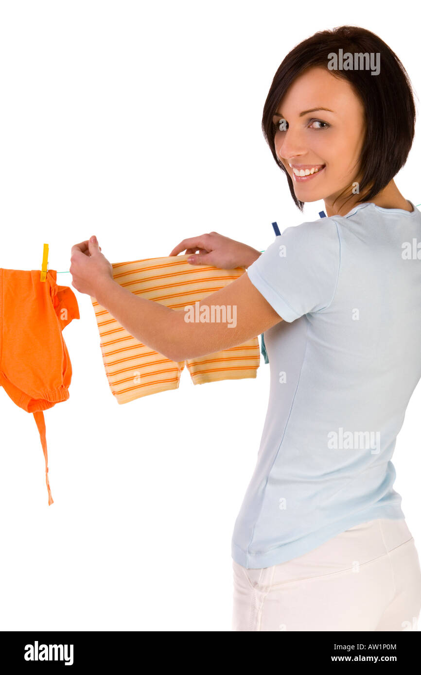 Young smiling woman hanging clothes on clothesline using clothespin ...