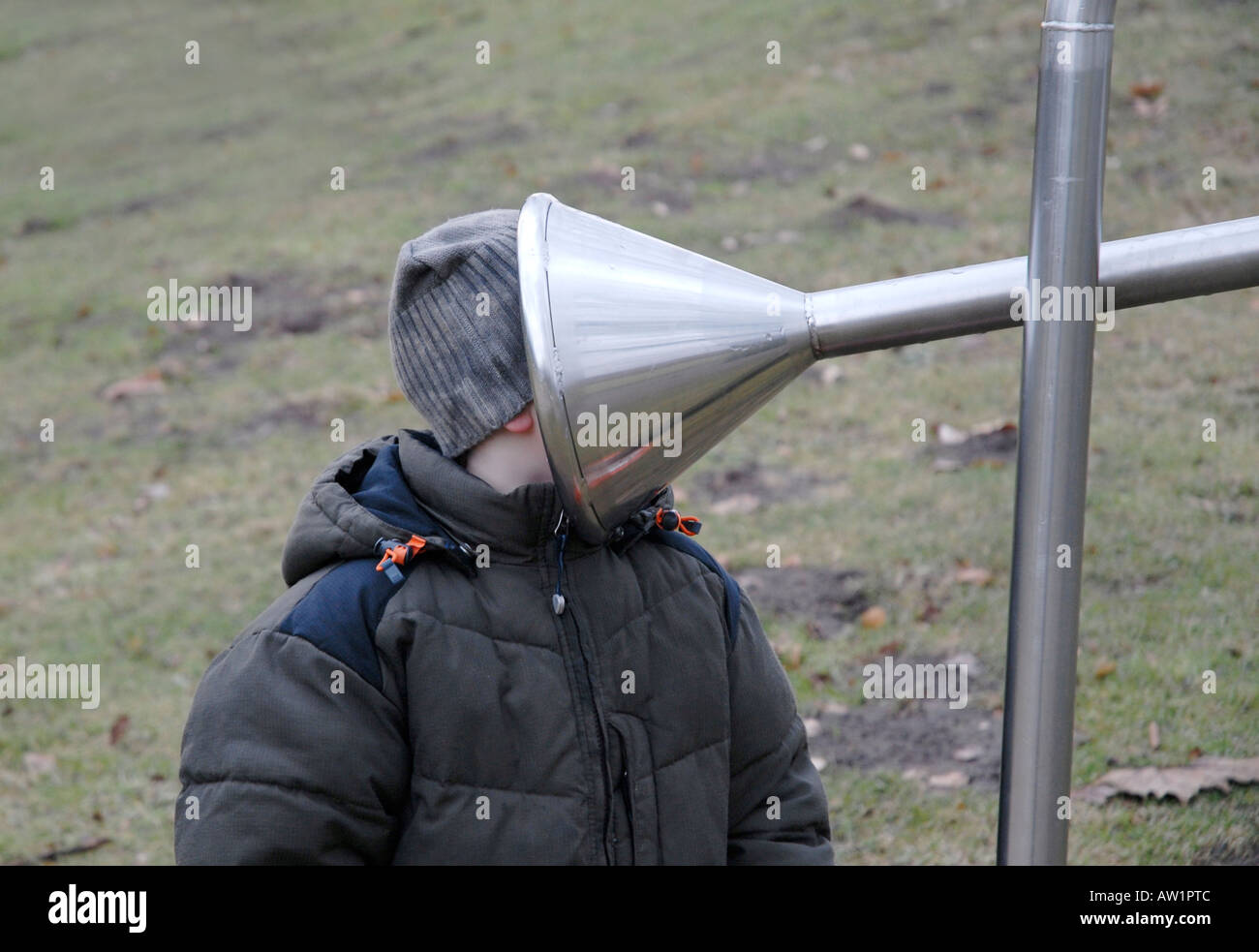 Little boy sticking his head into the funnel of an intercom in a ...