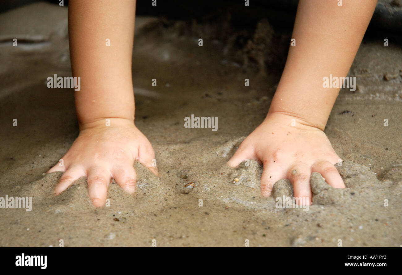 Little hands playing with wet sand Stock Photo - Alamy
