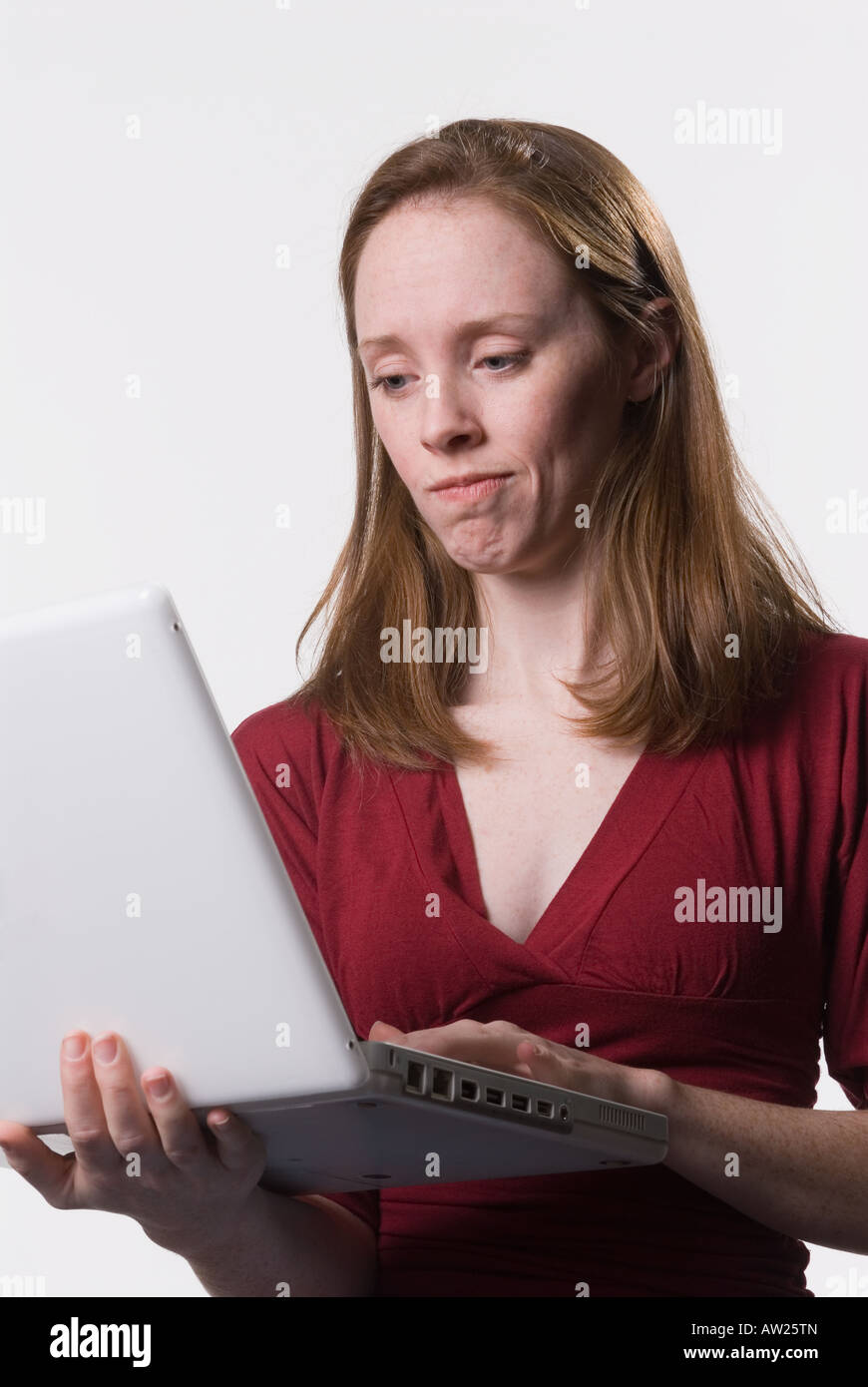 a young woman looks down at her laptop computer screen with a ...
