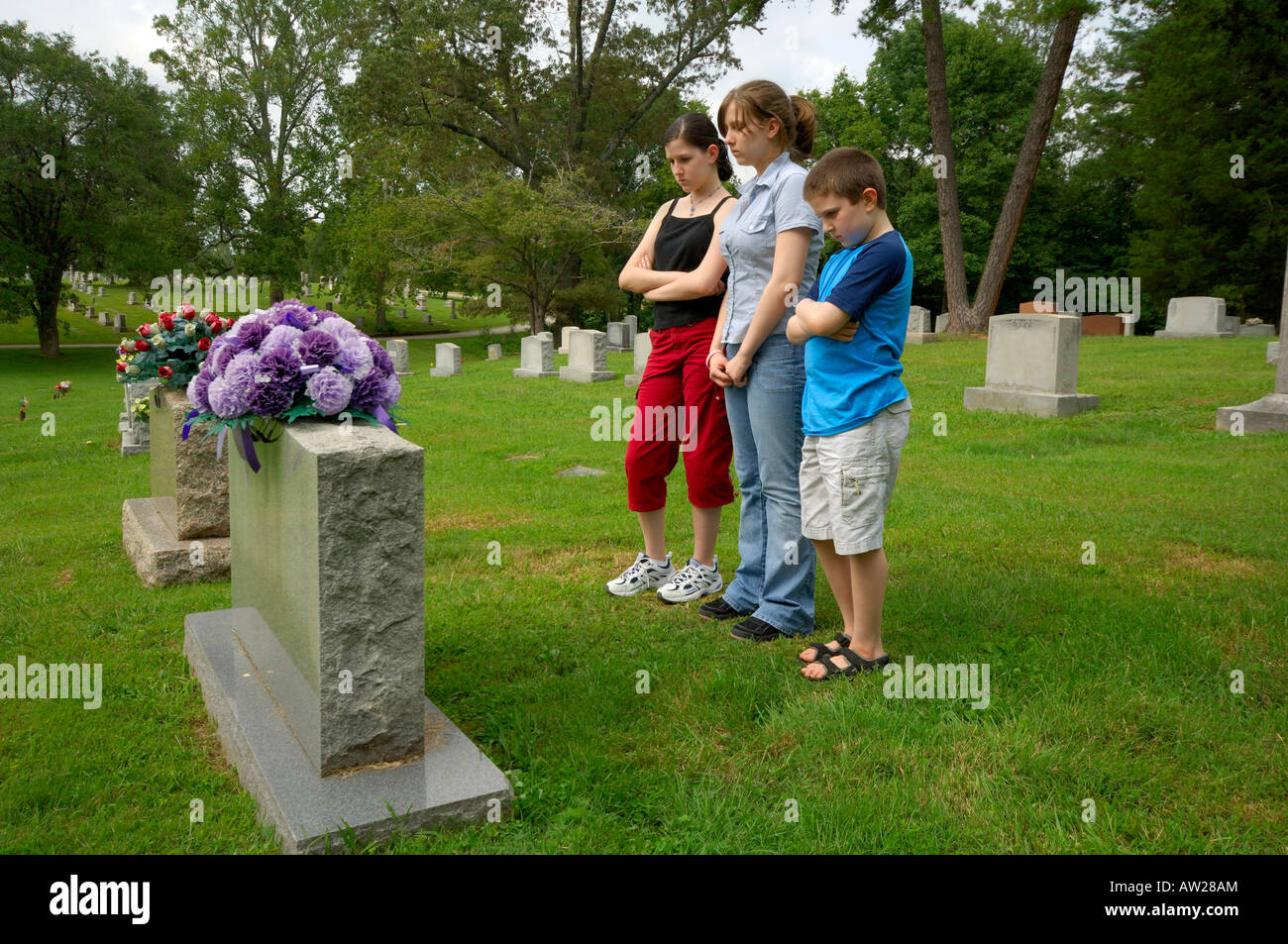 Three children mourn the loss of a family member. The young ones gaze ...