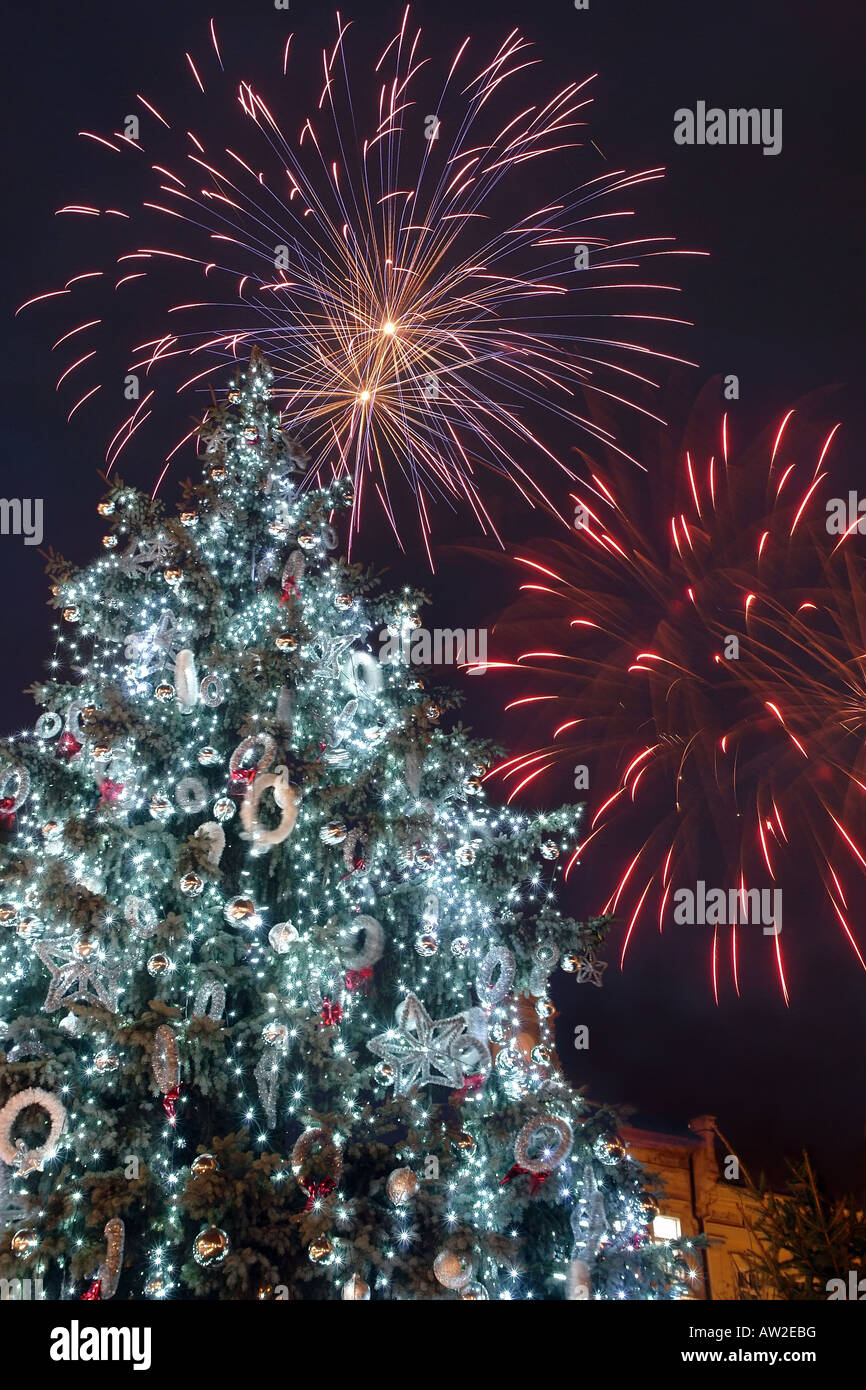 Illuminated giant outdoor xmas tree and fireworks bursting above in the ...