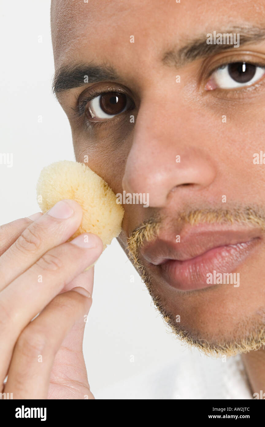 Man using sponge on his face Stock Photo - Alamy