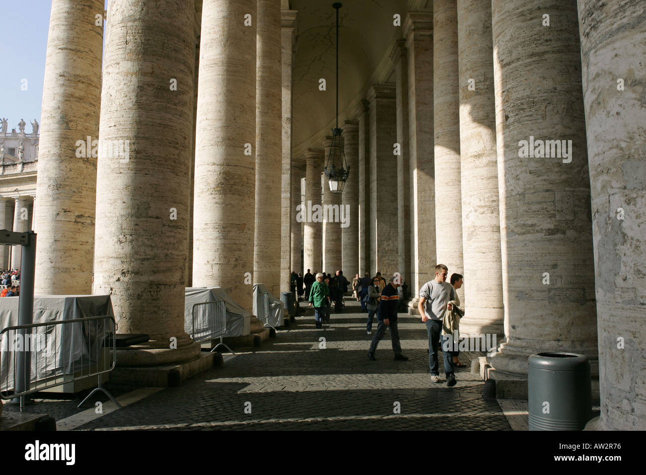 Tourists explore the white stone columns surrounding St Peters Square ...